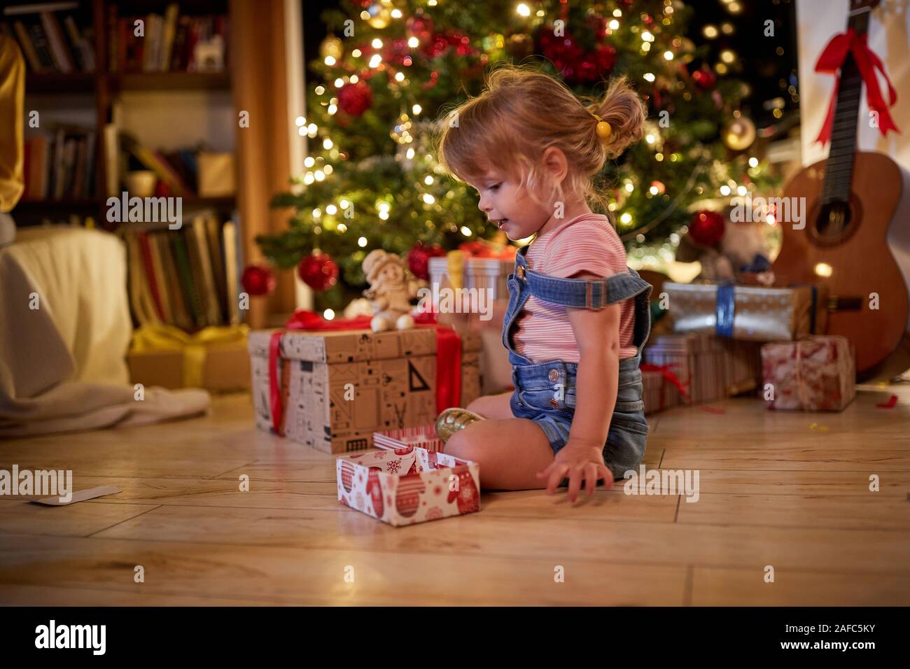 child girl open presents in a room with a Christmas tree on Christmas ...