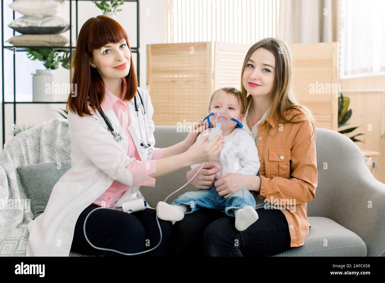 One year old baby girl getting a nebulizer treatment from a doctor ...