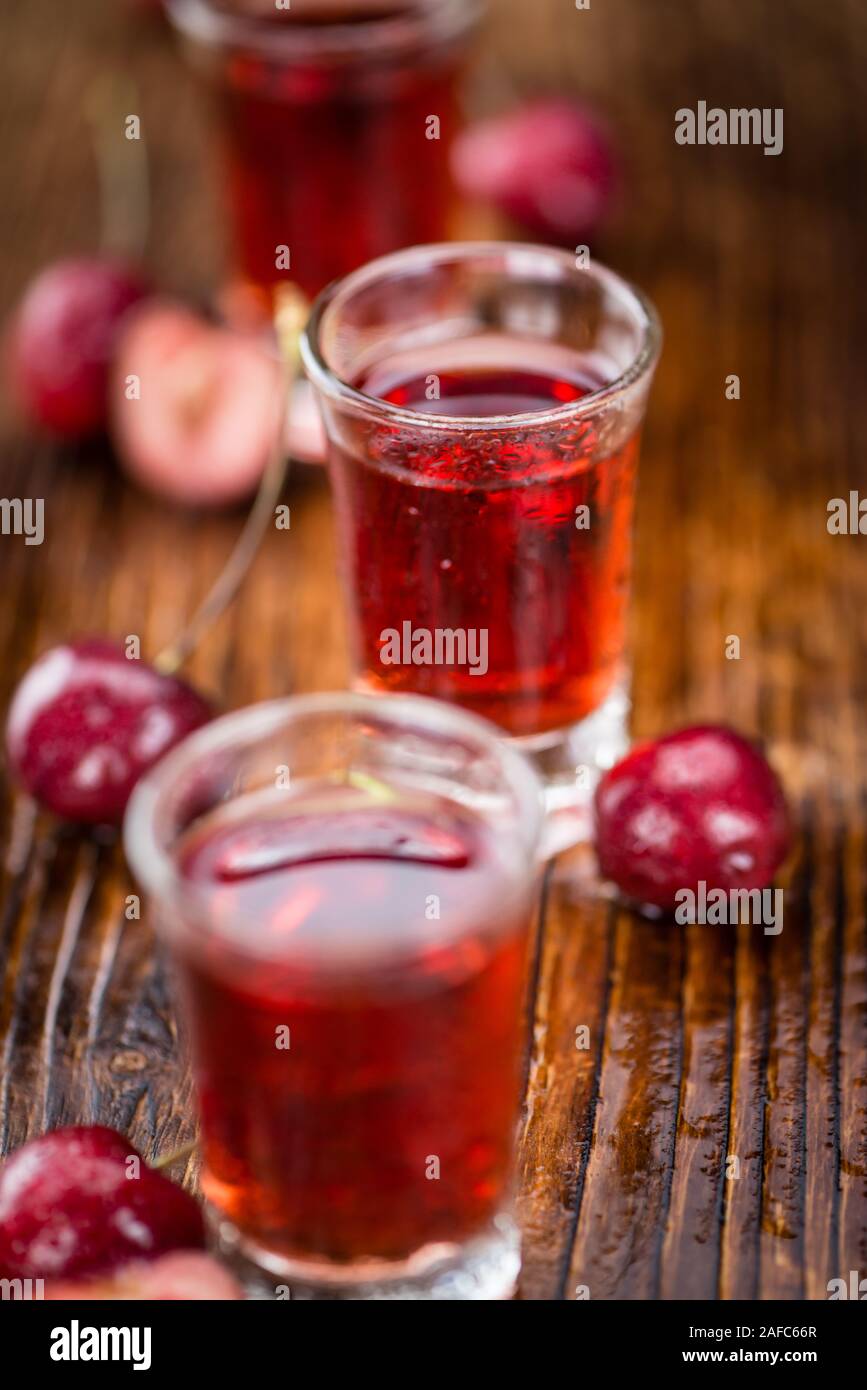 Homemade Cherry Liqueur on an wooden table as detailed close-up shot ...