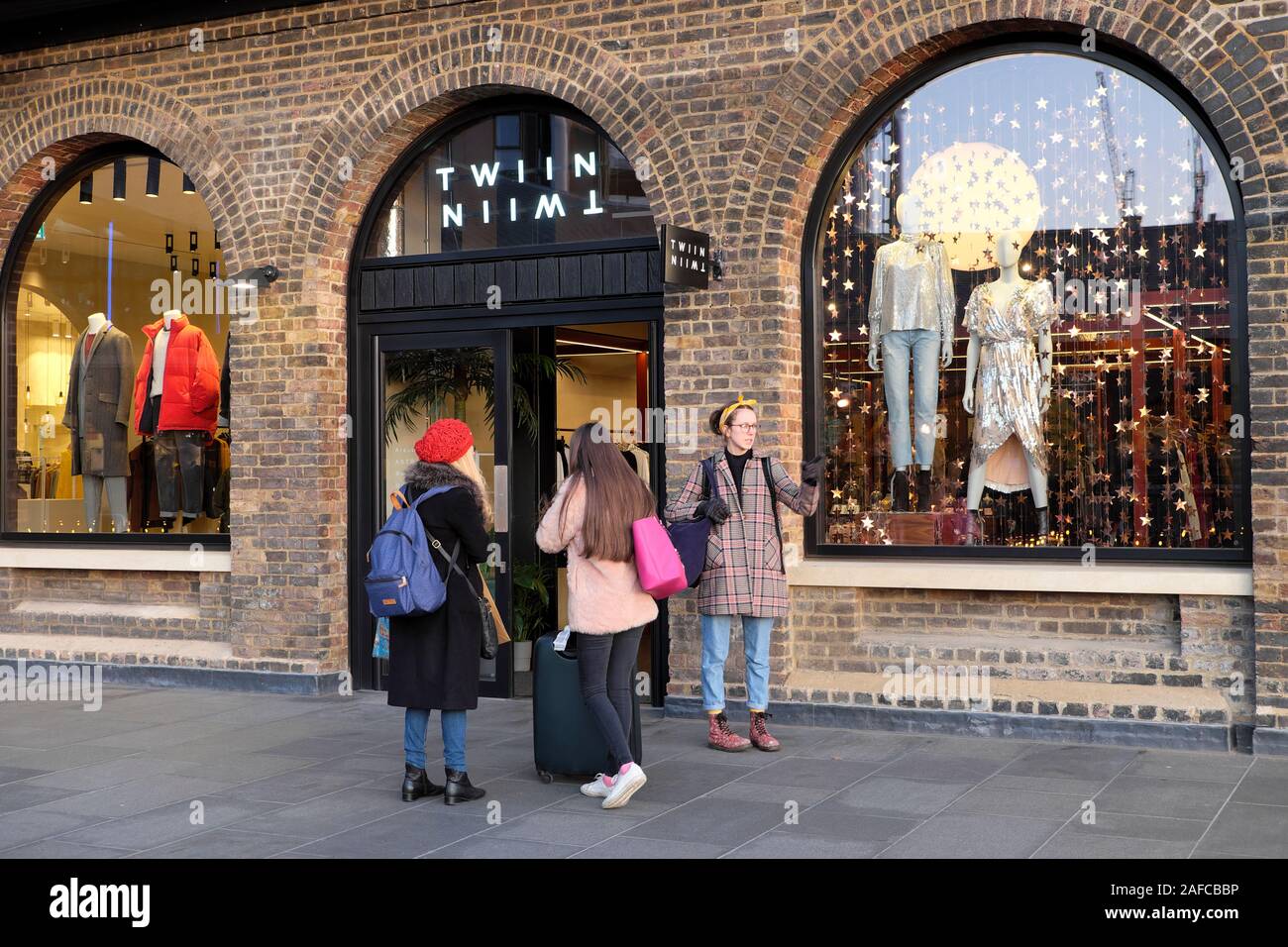 Young women Christmas shopping standing at the entrance to the designer ...