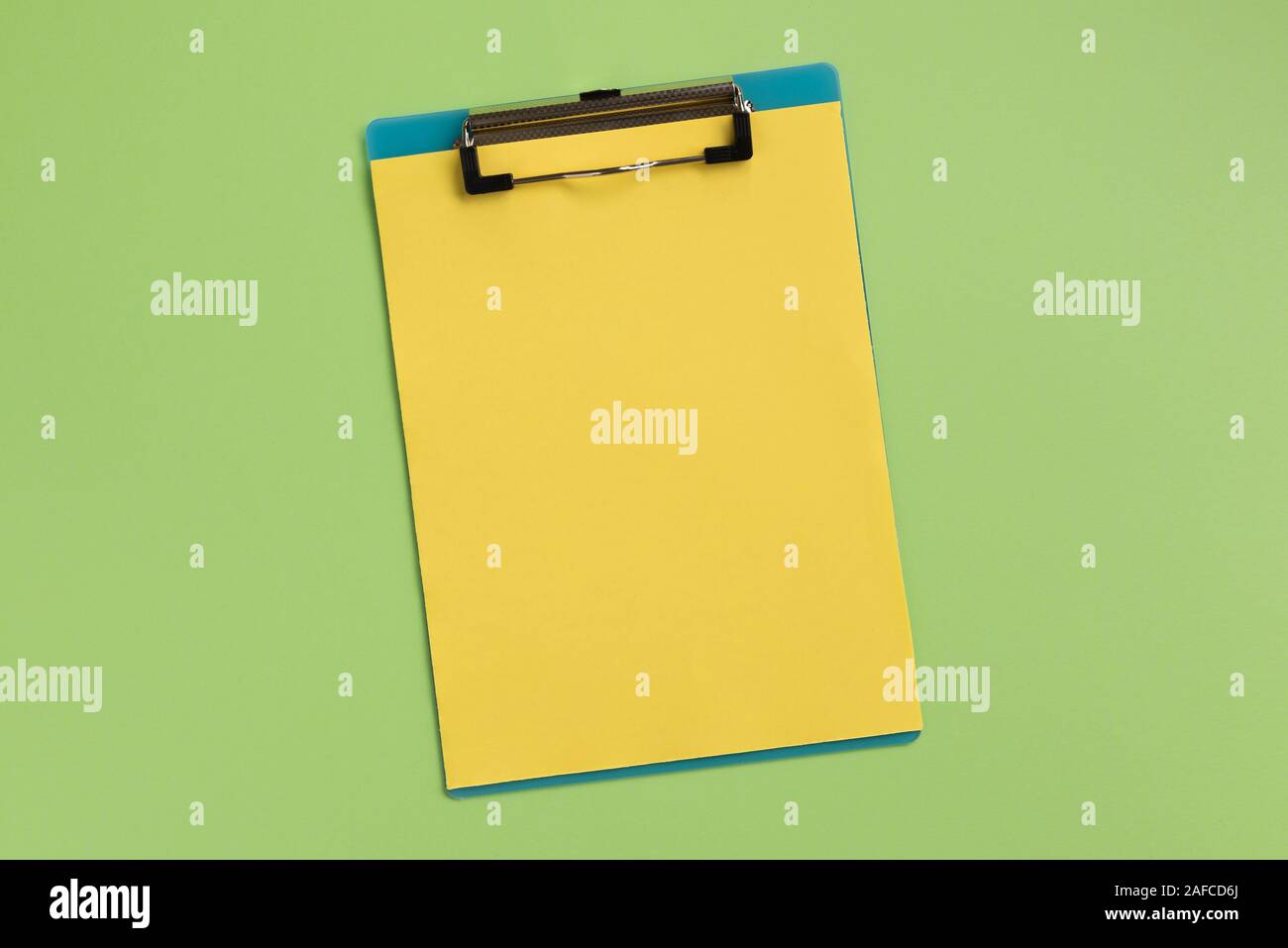 Clipboard with yellow sheet, on green background. Flat lay, top view ...