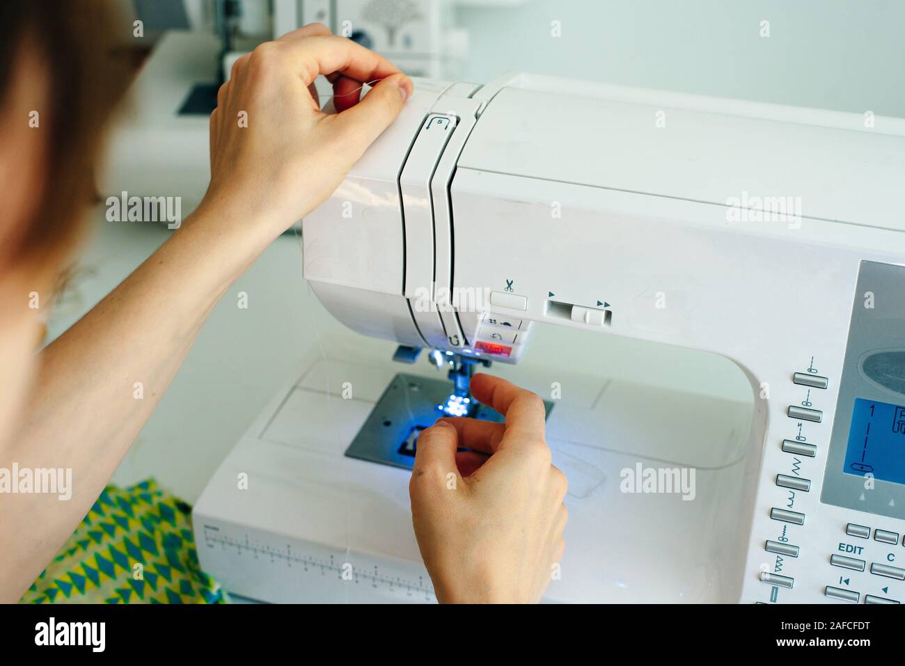 Female hands stitching white fabric on professional manufacturing ...