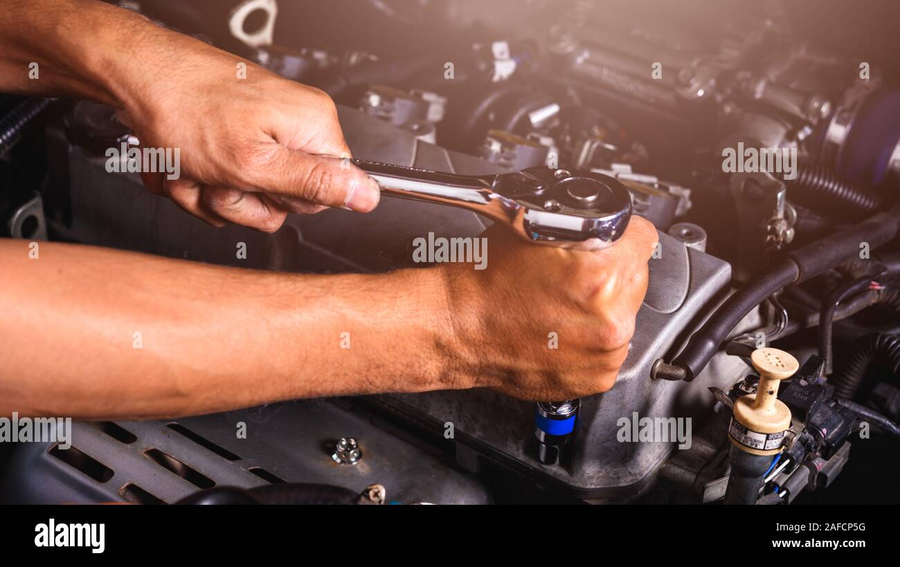 Hand of auto mechanic technician service engine and using wrench socket ...