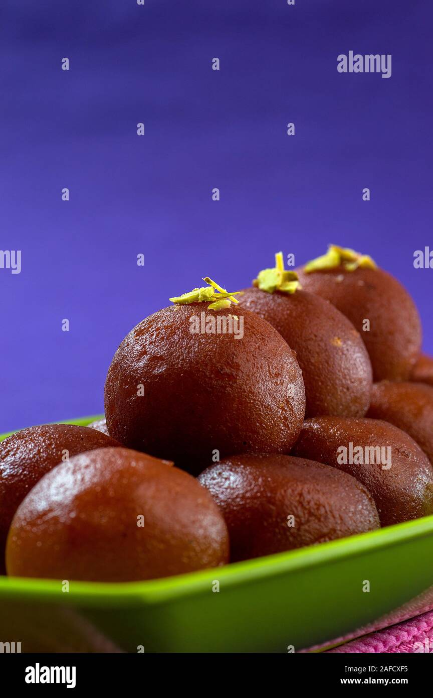 Indian Dessert Gulab Jamun in plate on purple background with napkin ...