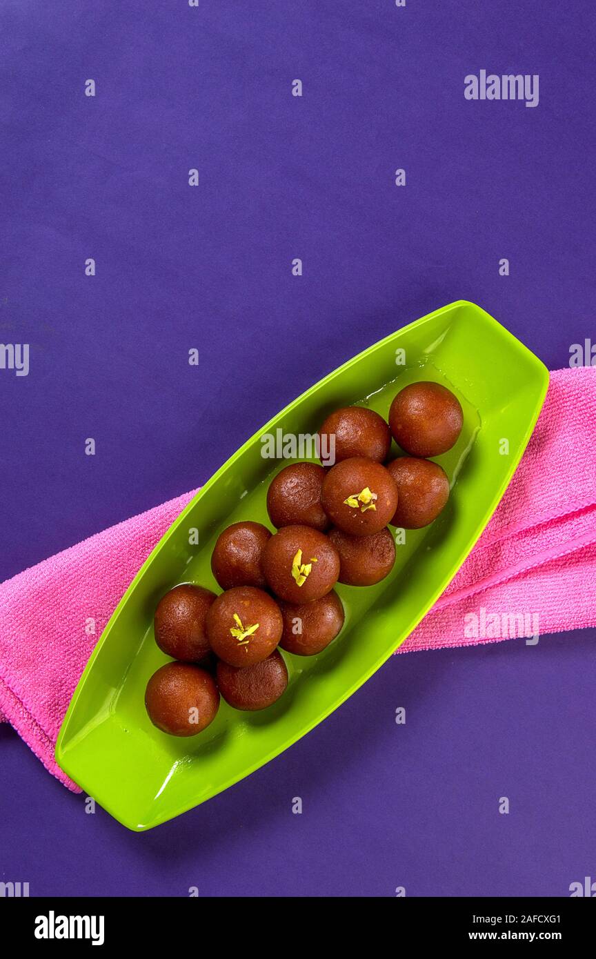 Indian Dessert Gulab Jamun in plate on purple background with napkin ...