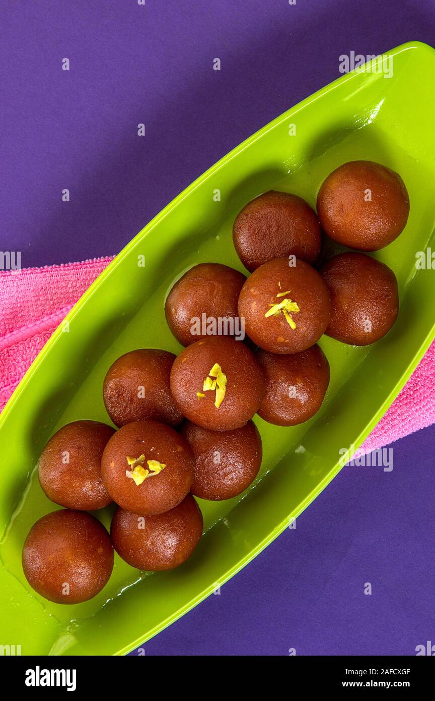 Indian Dessert Gulab Jamun in plate on purple background with napkin ...