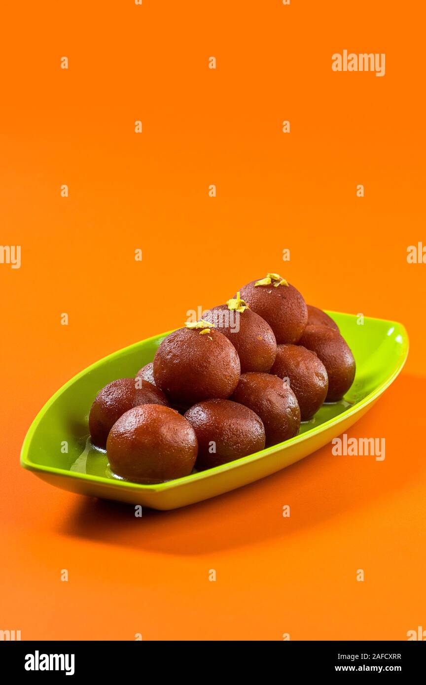 Indian Dessert Gulab Jamun in plate on orange background Stock Photo ...