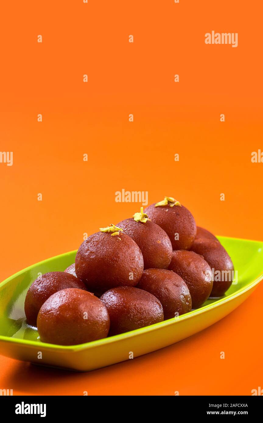 Indian Dessert Gulab Jamun in plate on orange background Stock Photo ...