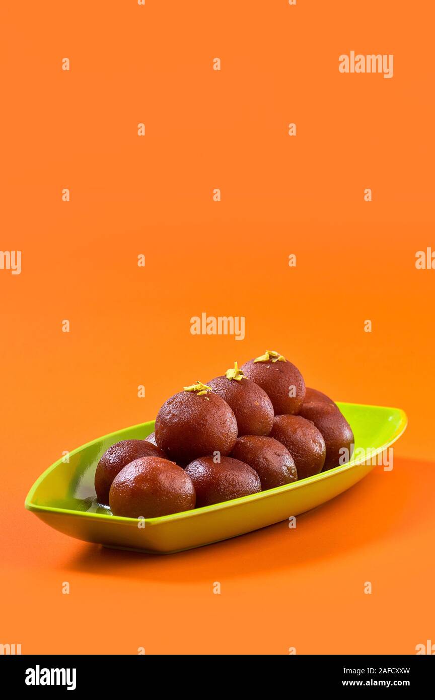 Indian Dessert Gulab Jamun in plate on orange background Stock Photo ...
