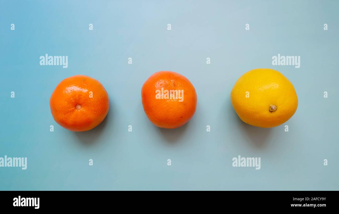 Two small mandarin oranges and a yellow lemon arranged side by side in ...