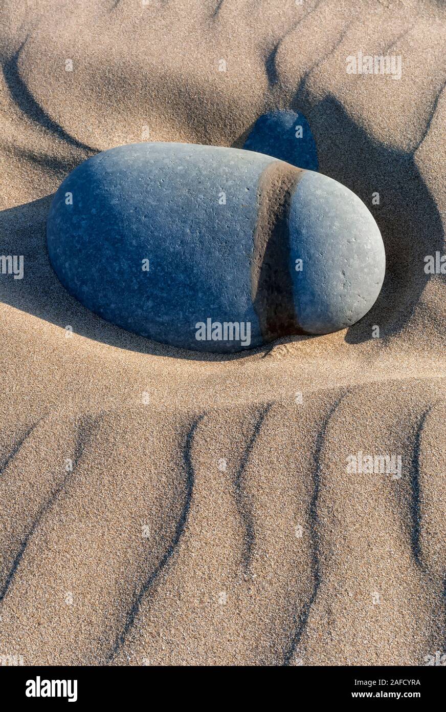 Lone pebbles on the beach surrounded by sand patterns Stock Photo - Alamy