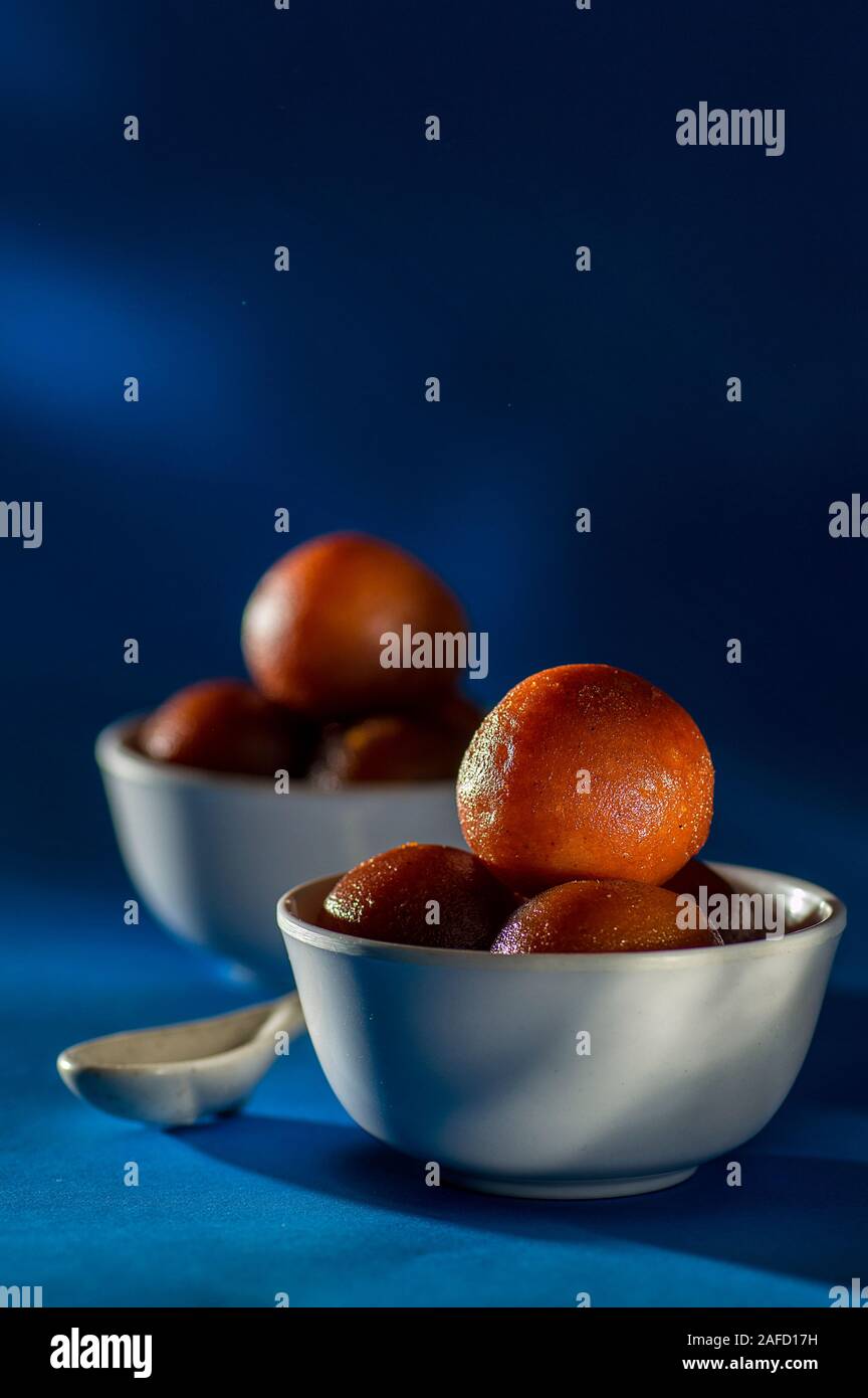 Indian Dessert : Gulab Jamun in bowl with spoon on blue background ...