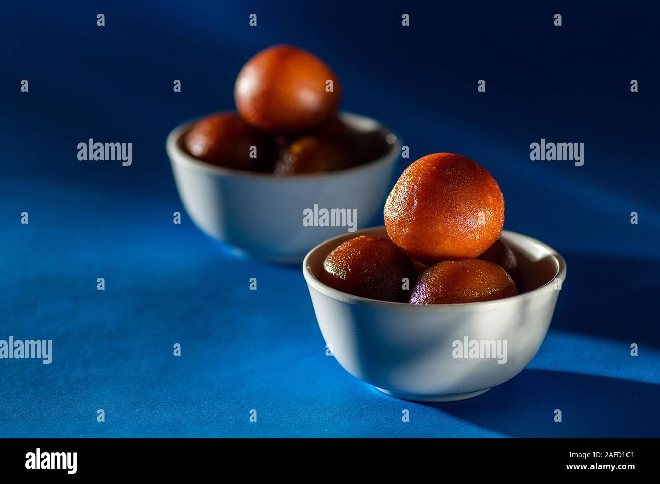 Indian Dessert : Gulab Jamun in bowl with spoon on blue background ...