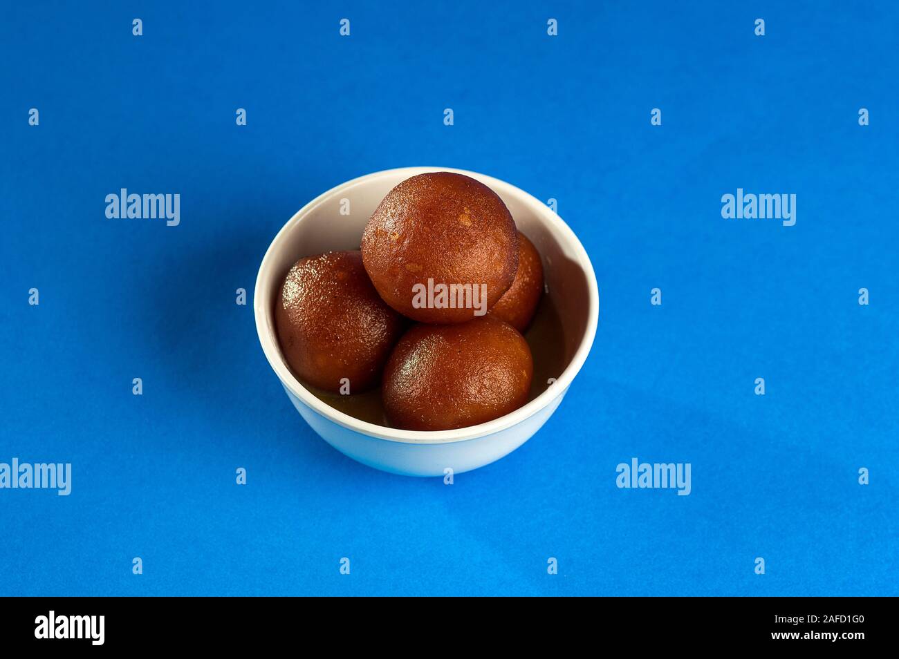 Indian Dessert : Gulab Jamun in bowl with spoon on blue background ...
