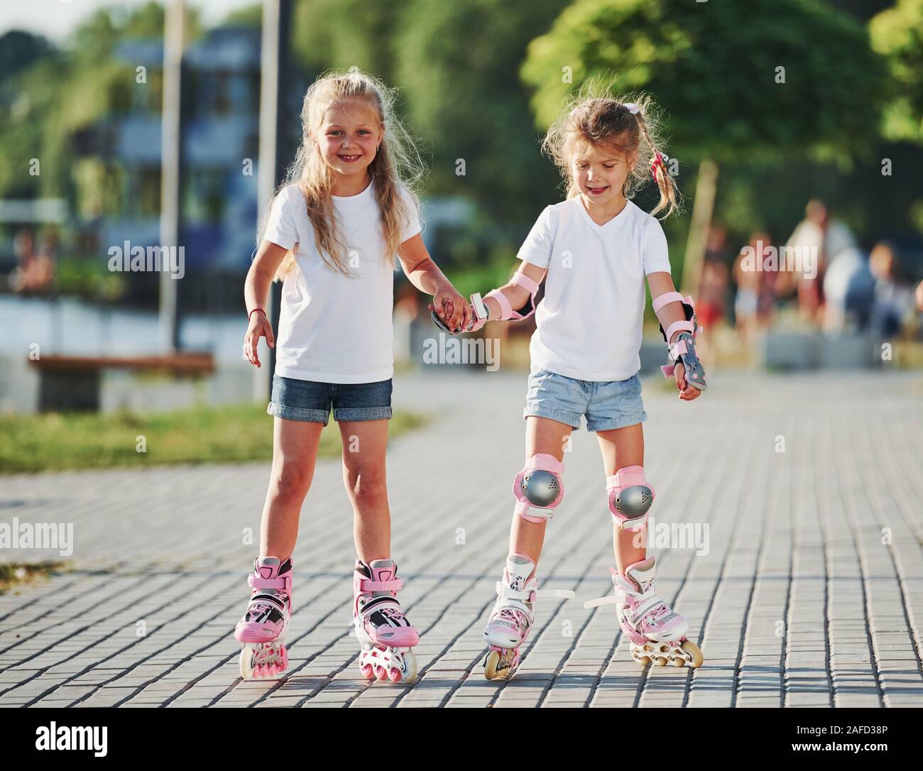 Two cute kids riding by roller skates in the park at daytime Stock ...