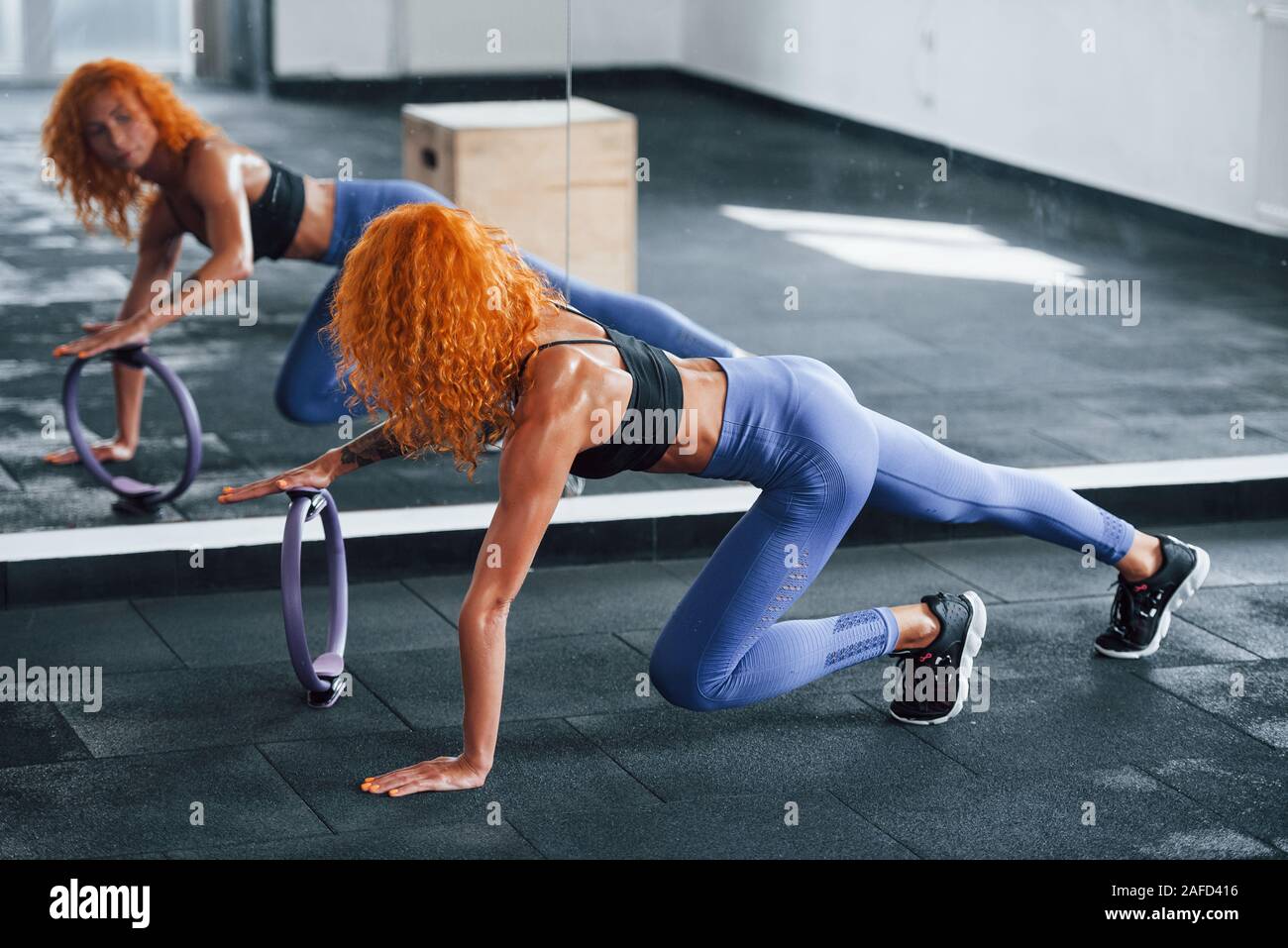 With special equipment. Sporty redhead girl have fitness day in gym at ...