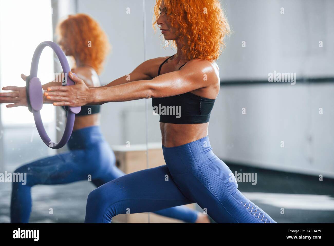 With special equipment. Sporty redhead girl have fitness day in gym at ...