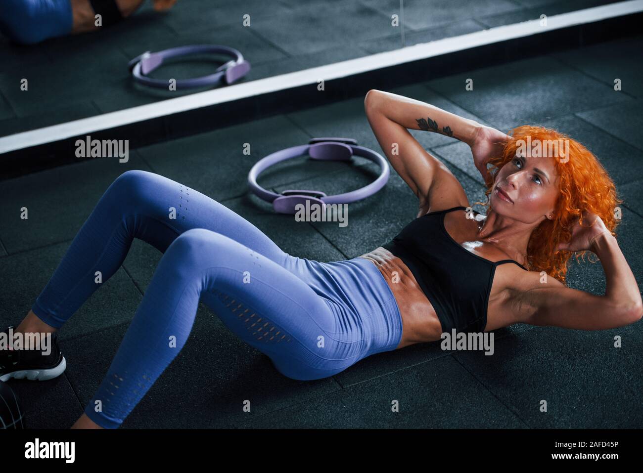 Concentrated at exercise. Sporty redhead girl have fitness day in gym ...