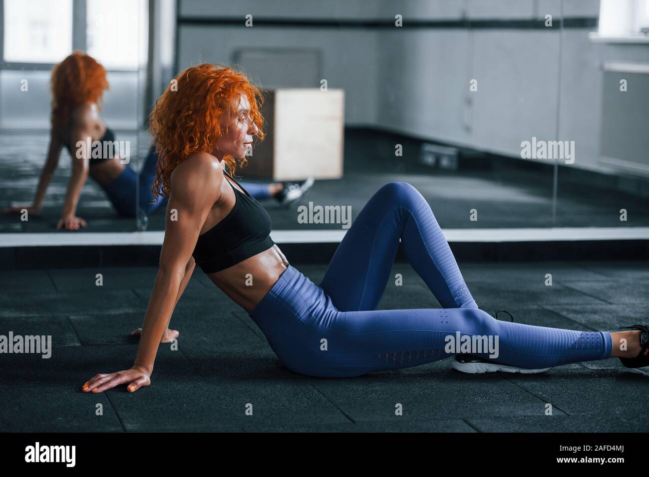 Sporty redhead girl have fitness day in gym at daytime. Muscular body ...
