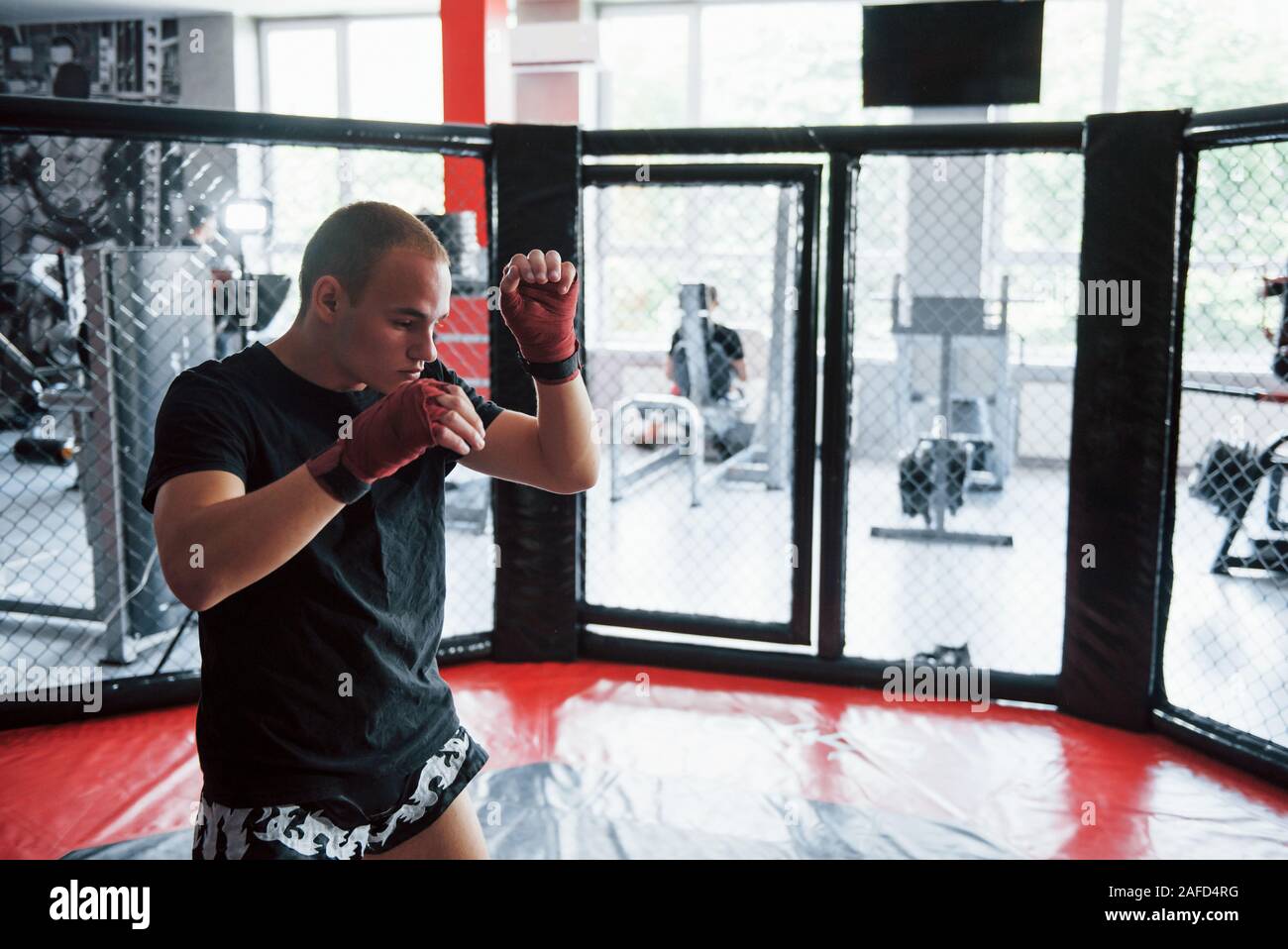 Young boxer in red bandages have exercise. In the gym on the cage Stock ...