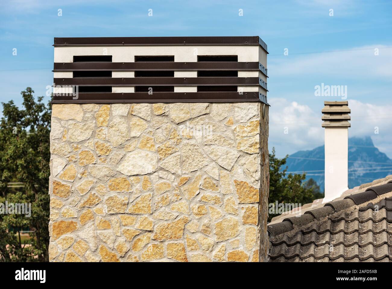 Close-up of two chimneys, one large and one small, on the roof of a ...