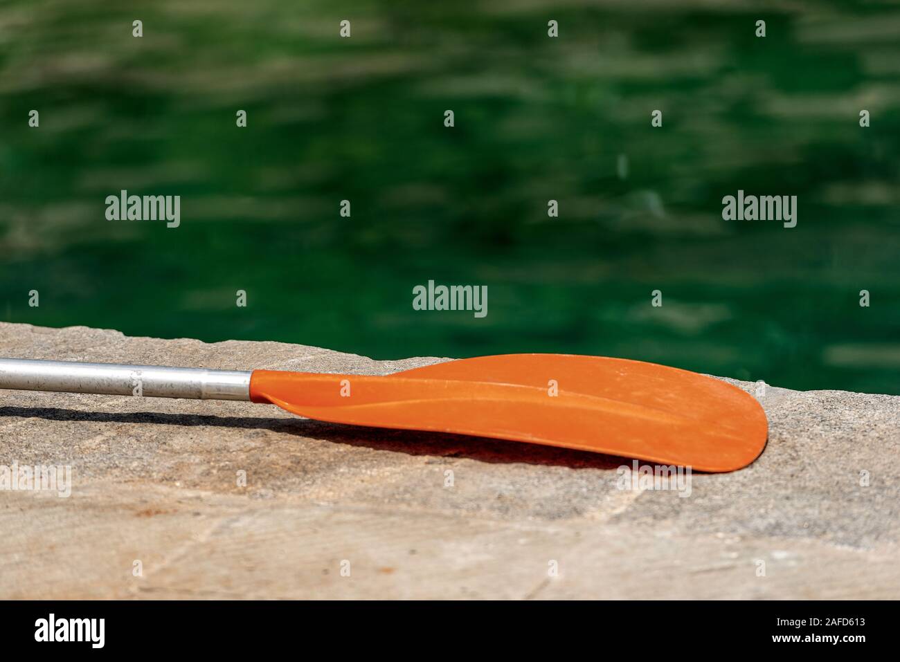 Detail of an orange paddle for kayak on the quay of the port with ...