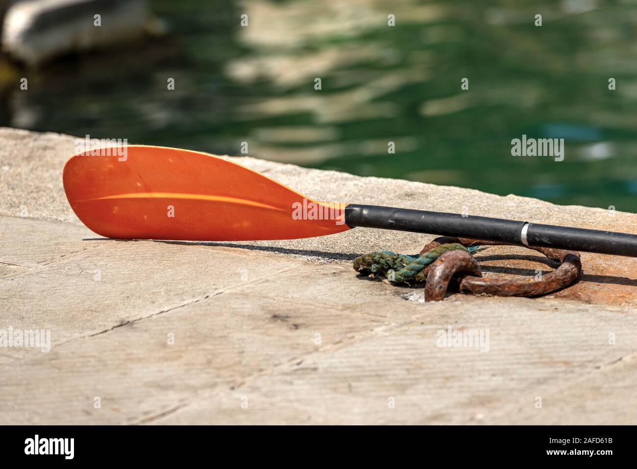Detail of a orange and red paddle for kayak on the quay of the port ...