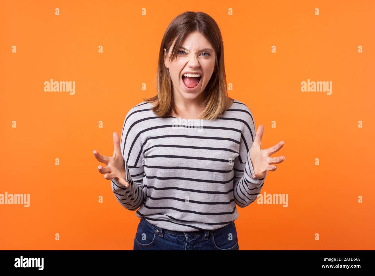 Portrait of angry, crazy young woman with brown hair in long sleeve ...