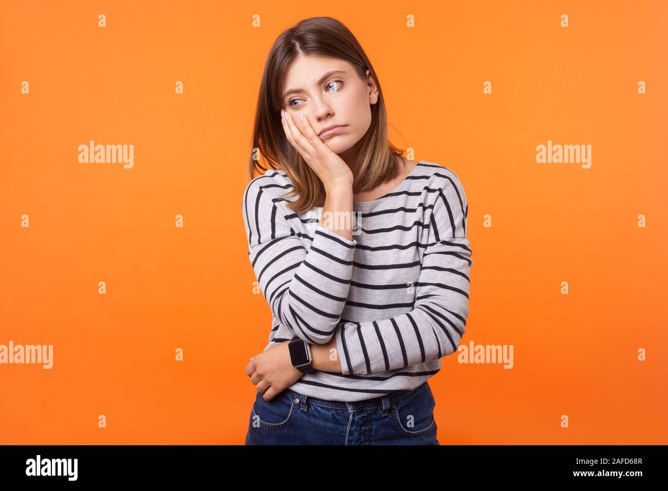 Portrait of bored young woman with brown hair in long sleeve shirt ...