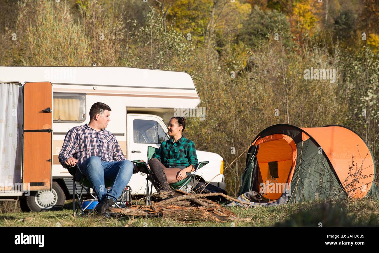Couple relaxing in a campsite with their retro camper van in the ...