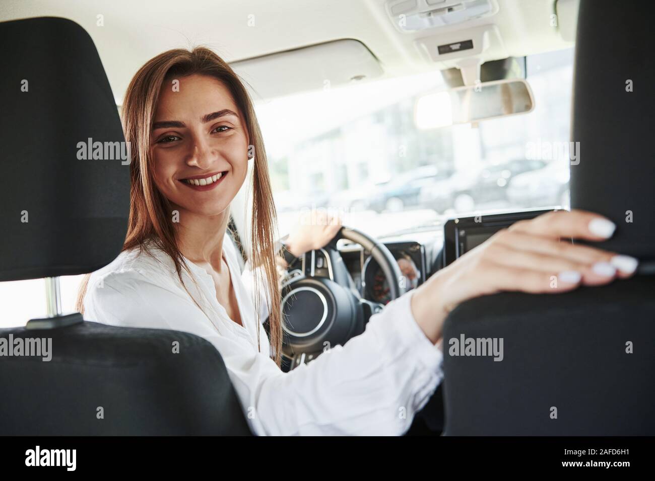 Cheerful female driver is in her new car. Interior of modern automobile ...