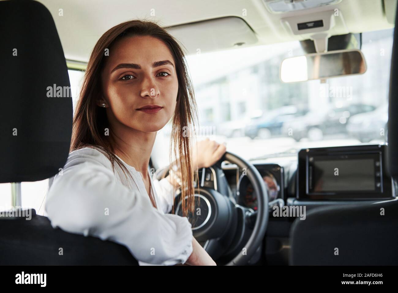 Cheerful female driver is in her new car. Interior of modern automobile ...