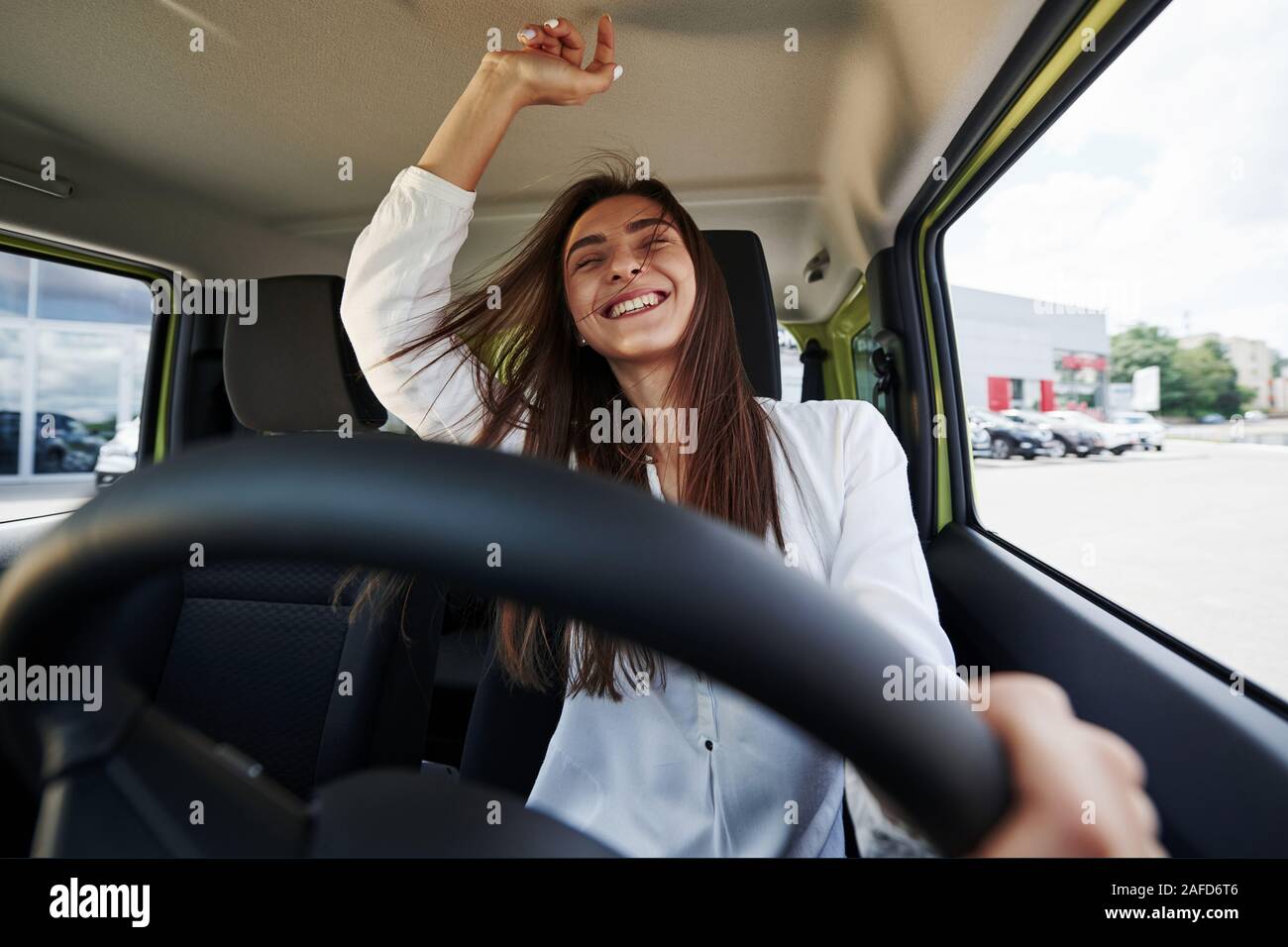 Happy owner. Front view of woman that drives modern new car in the city ...