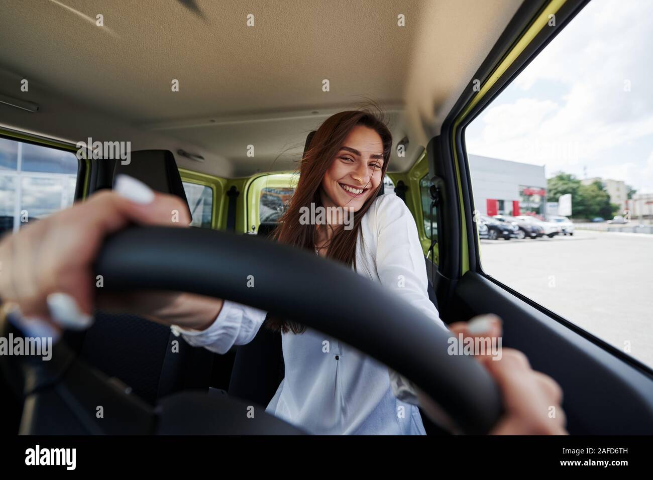 Happy owner. Front view of woman that drives modern new car in the city ...