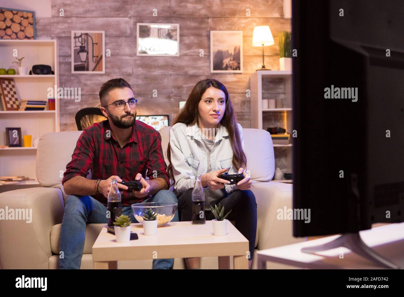 Relaxed couple playing video games on television using controllers ...