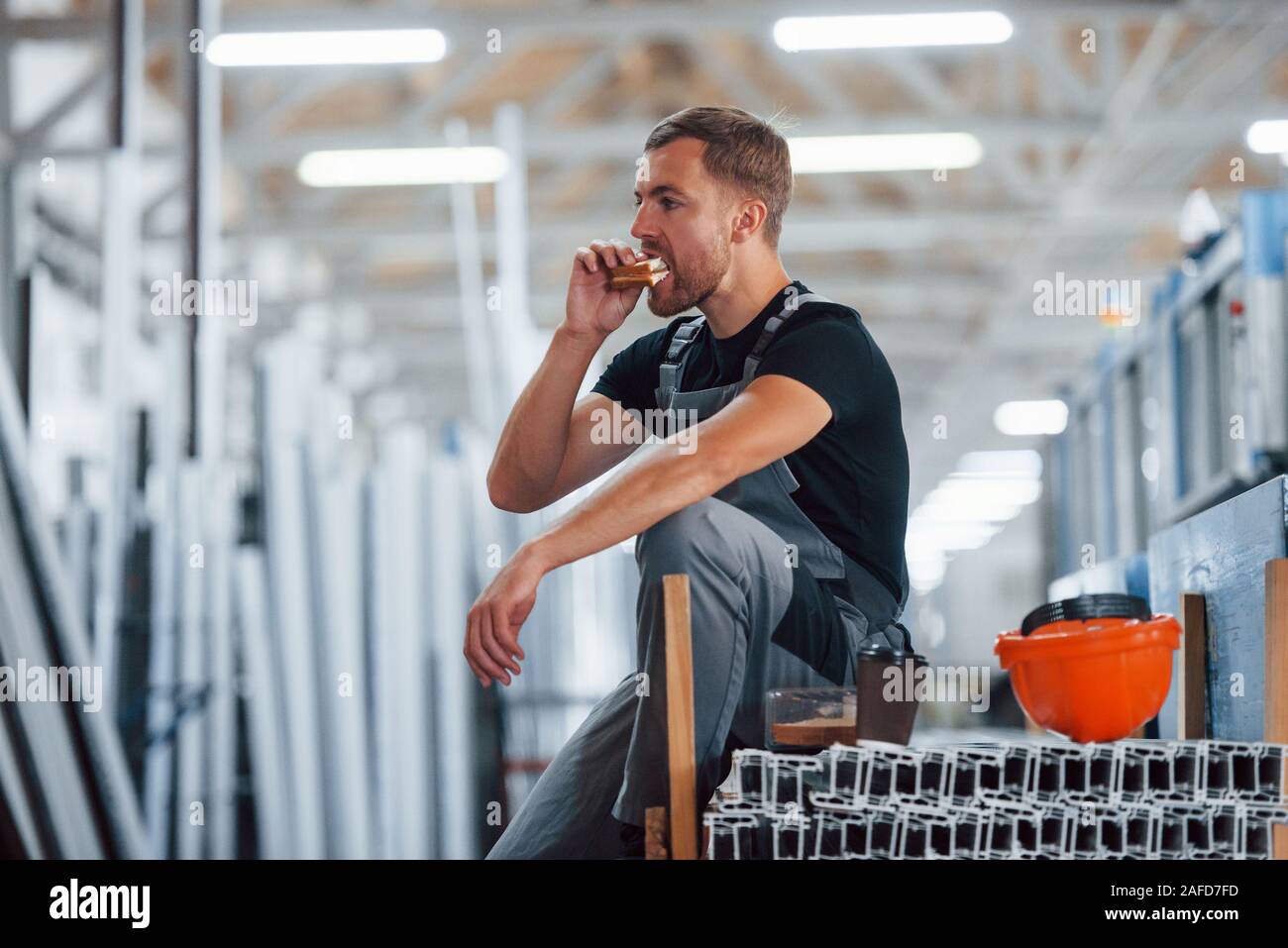 Lunch break. Eating and drinking. Industrial worker indoors in factory ...