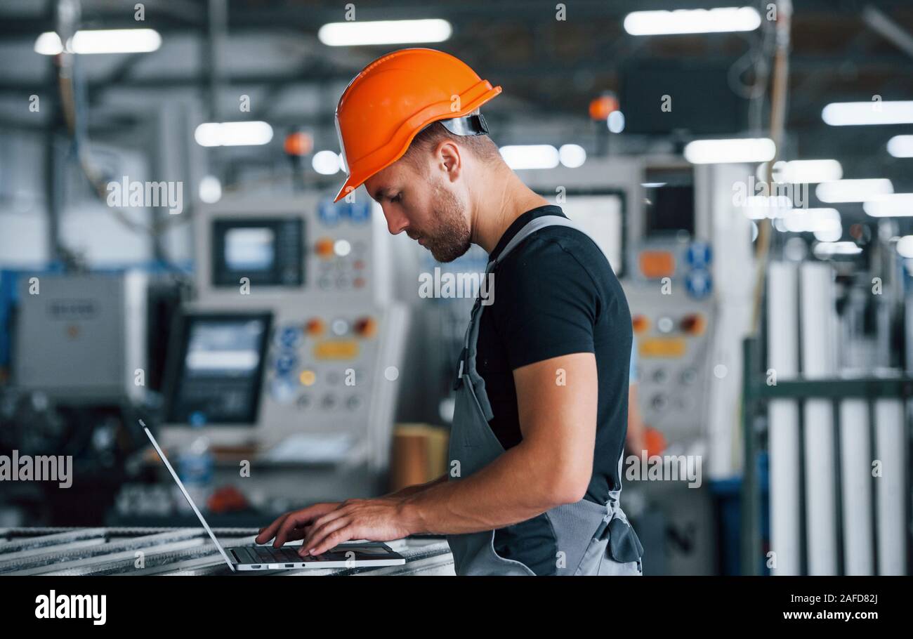 Modern laptop. Typing on keyboard. Industrial worker indoors in factory ...
