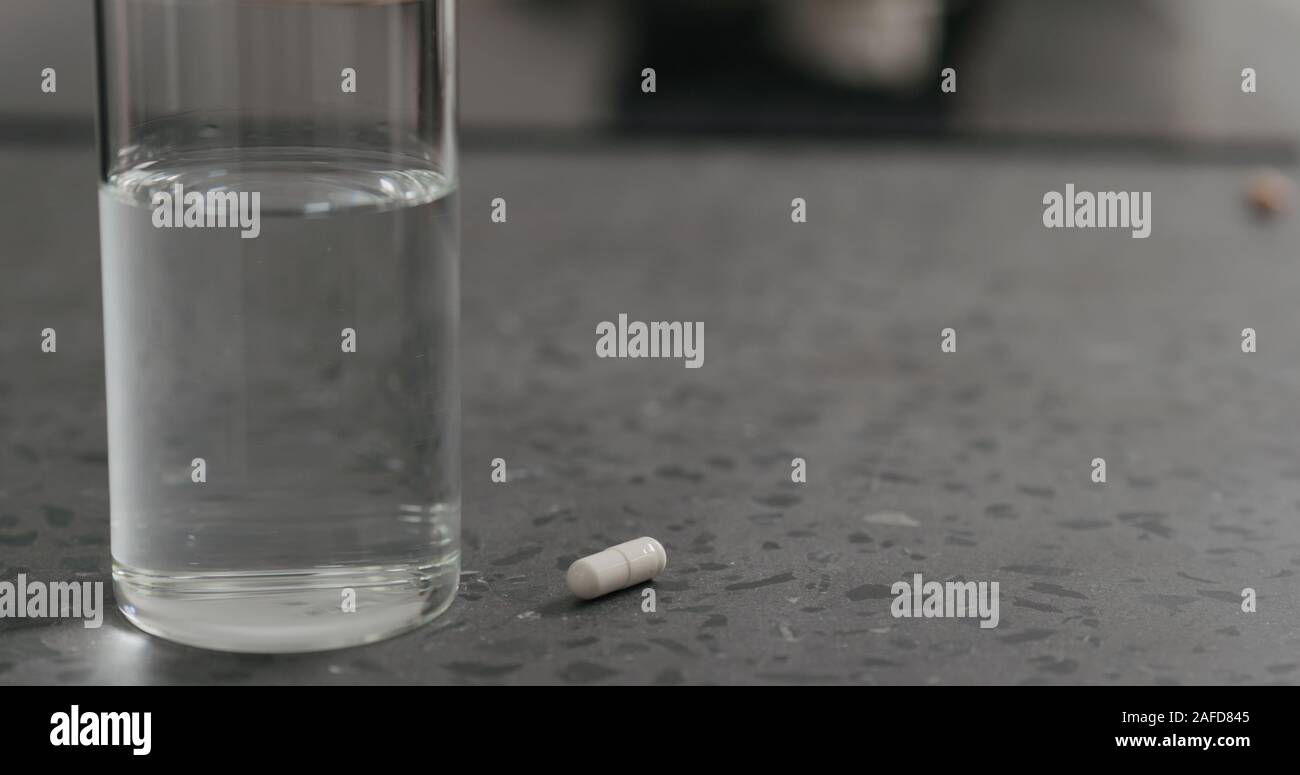 Glass of water and white pill on terrazzo countertop, wide photo Stock ...