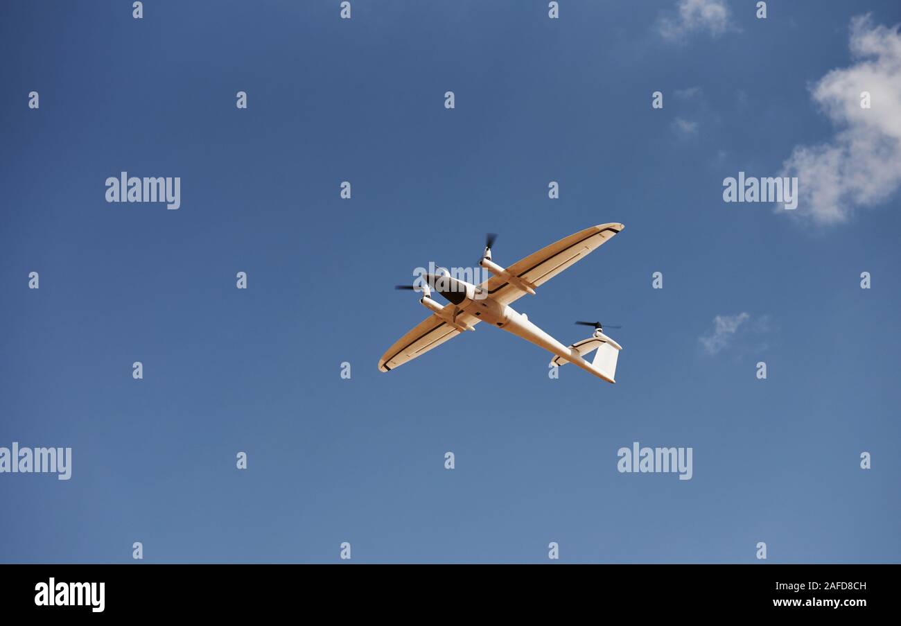 Modern small remote controlled white colored plane flying up in the sky ...
