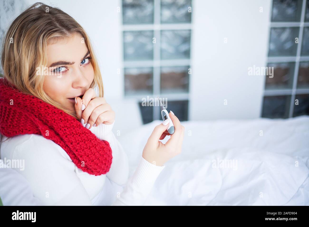 High temperature. Young woman looking at thermometer while holding it ...