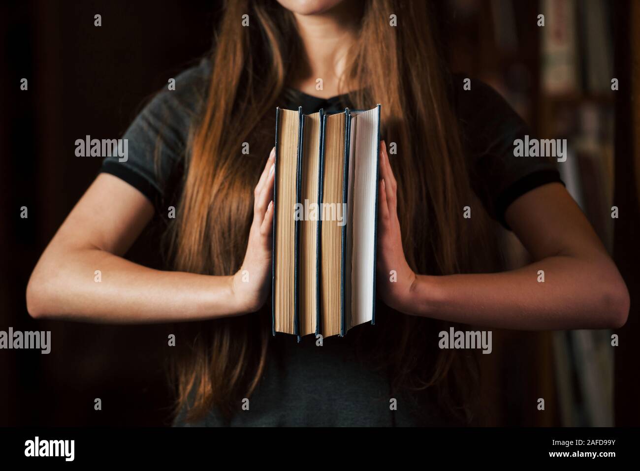 Holds many books in hands. Female student is in library. Conception of ...