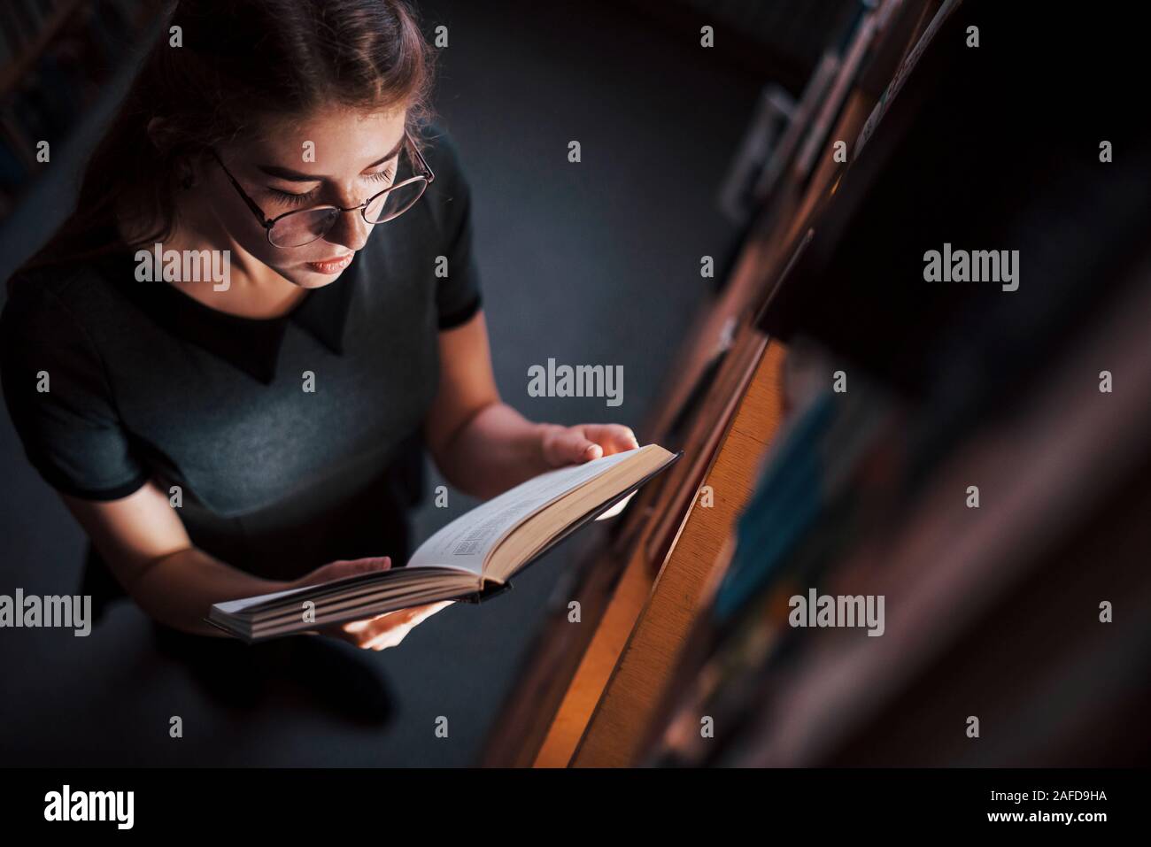 Aerial view. Female student is in library that full of books ...