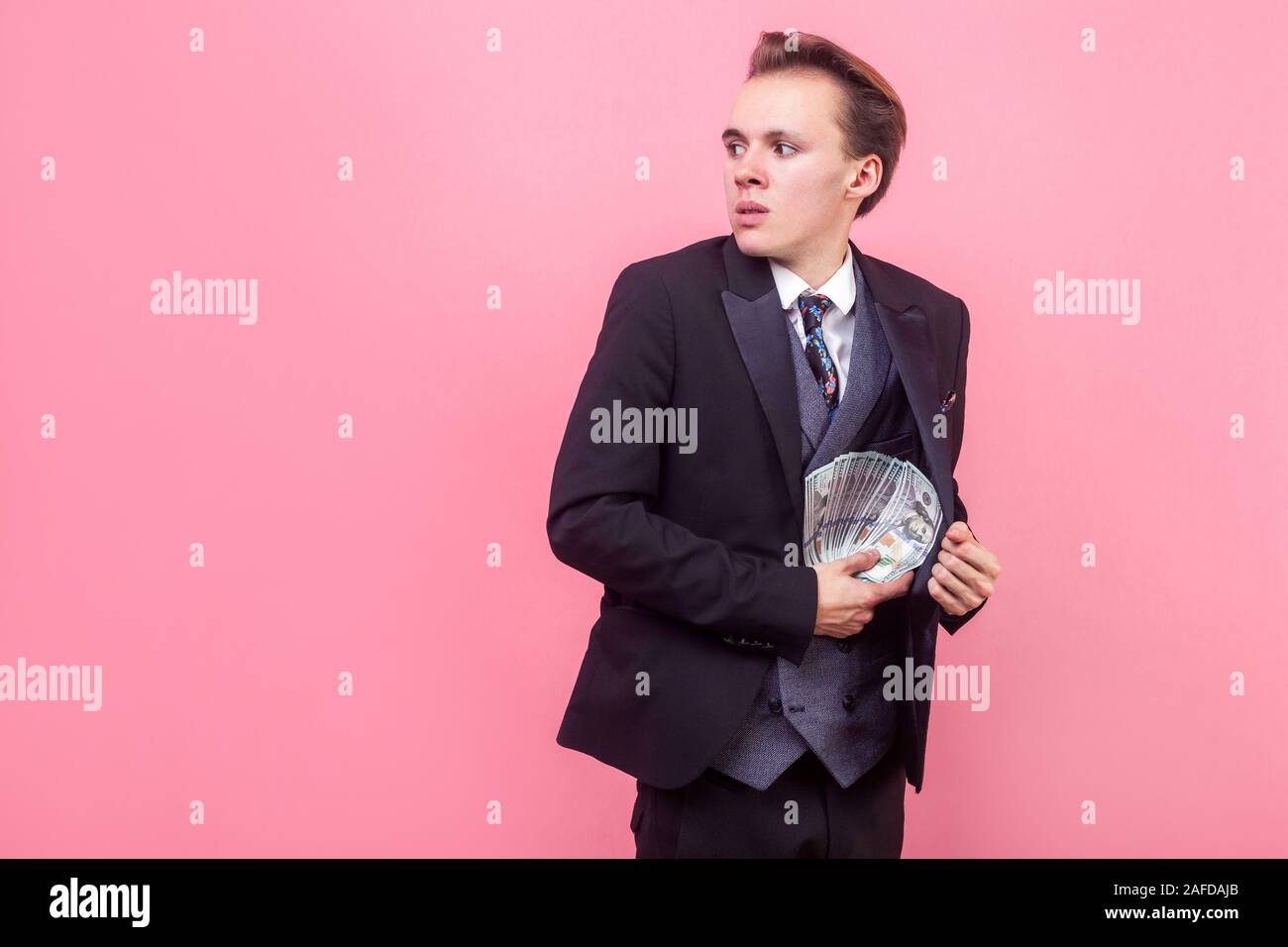 Portrait of scared greedy young businessman hiding dollar banknotes in ...