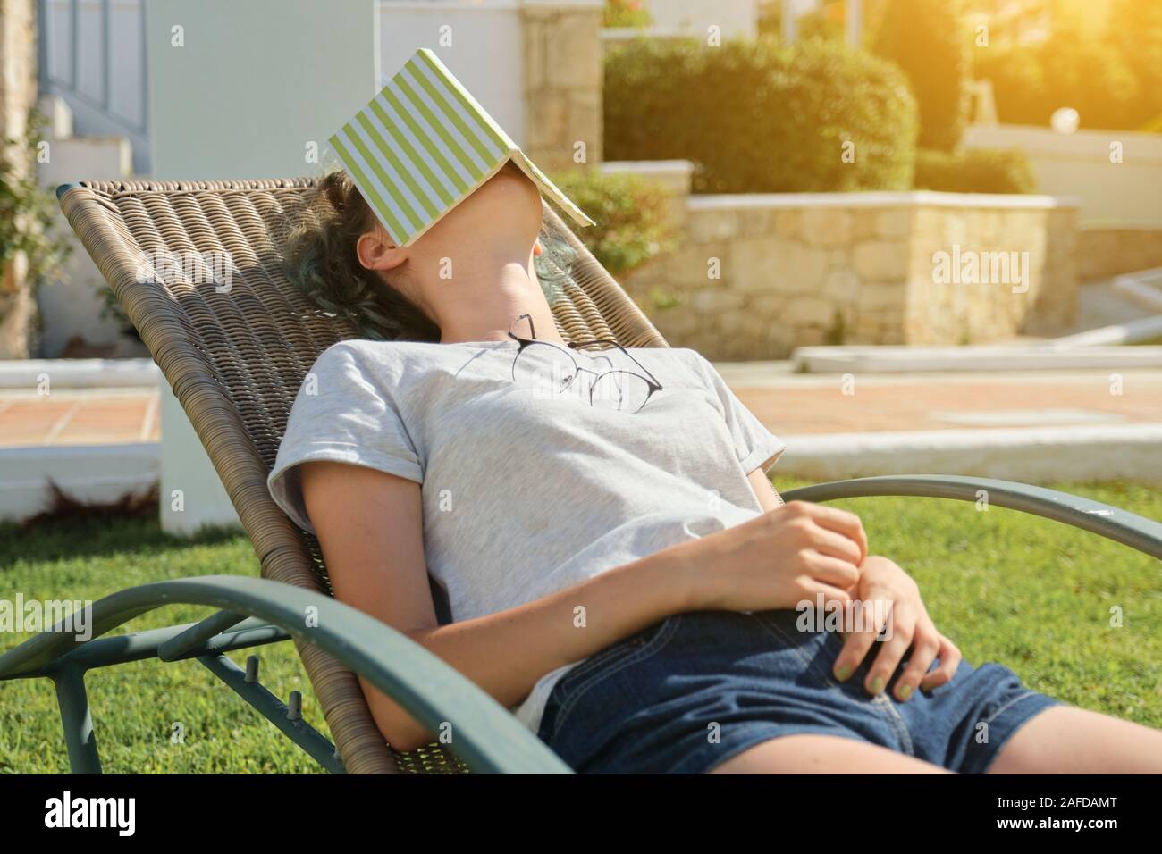 Teen girl resting outdoor sitting in chair, reading book and sleeping ...