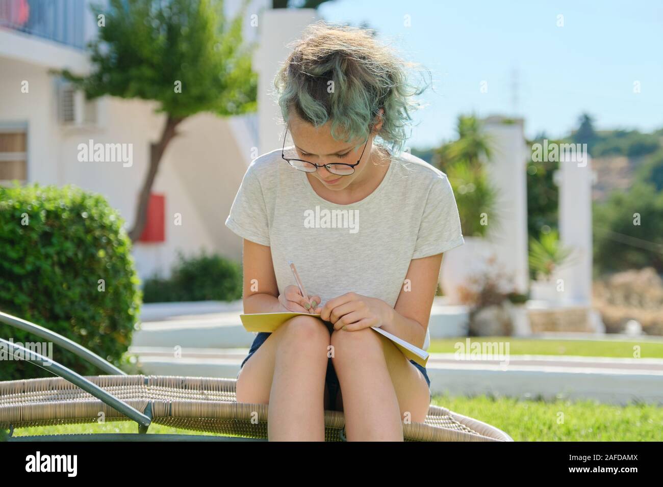 Student girl sitting outdoor, writing in school notebook Stock Photo ...