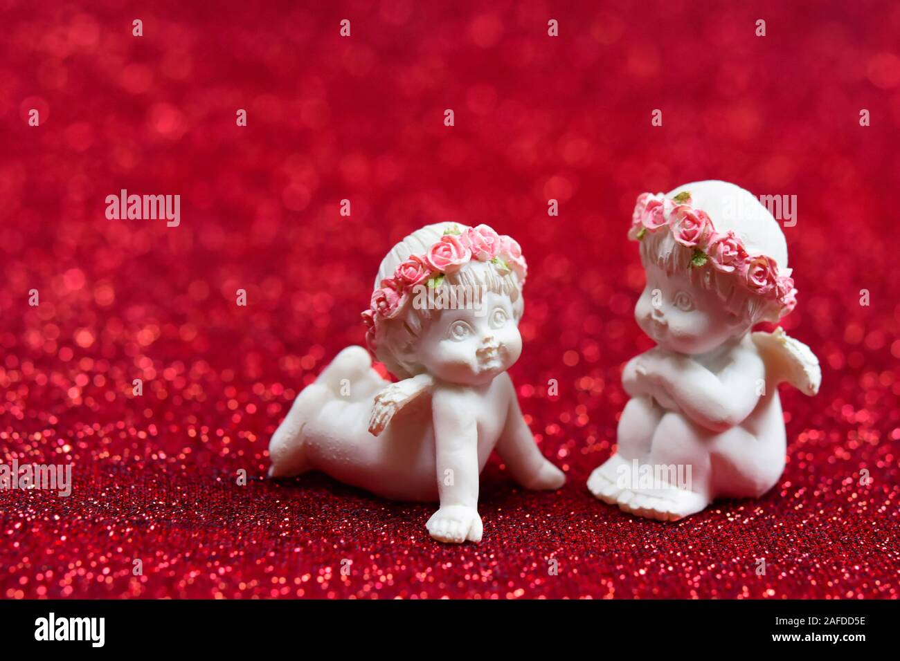 Little cupid or small angel sitting together on red bokeh background ...