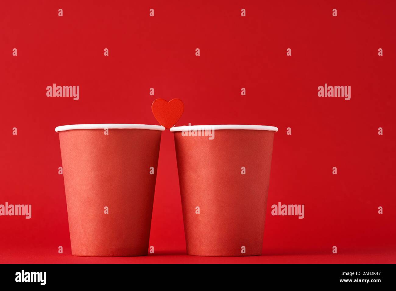 Two red coffee cups with heart as couple in love on red background ...