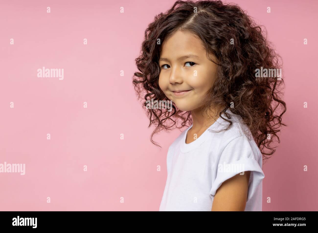 Closeup photo of curly haired funny little girl with sly look, smiling ...