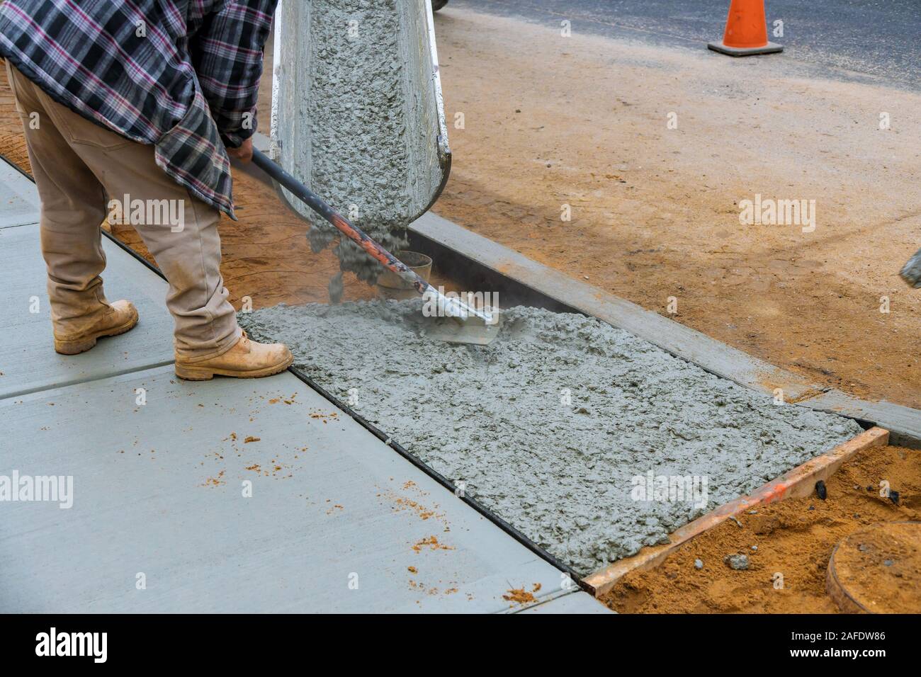 Construction worker pouring reinforced concrete cement for sidewalk in ...