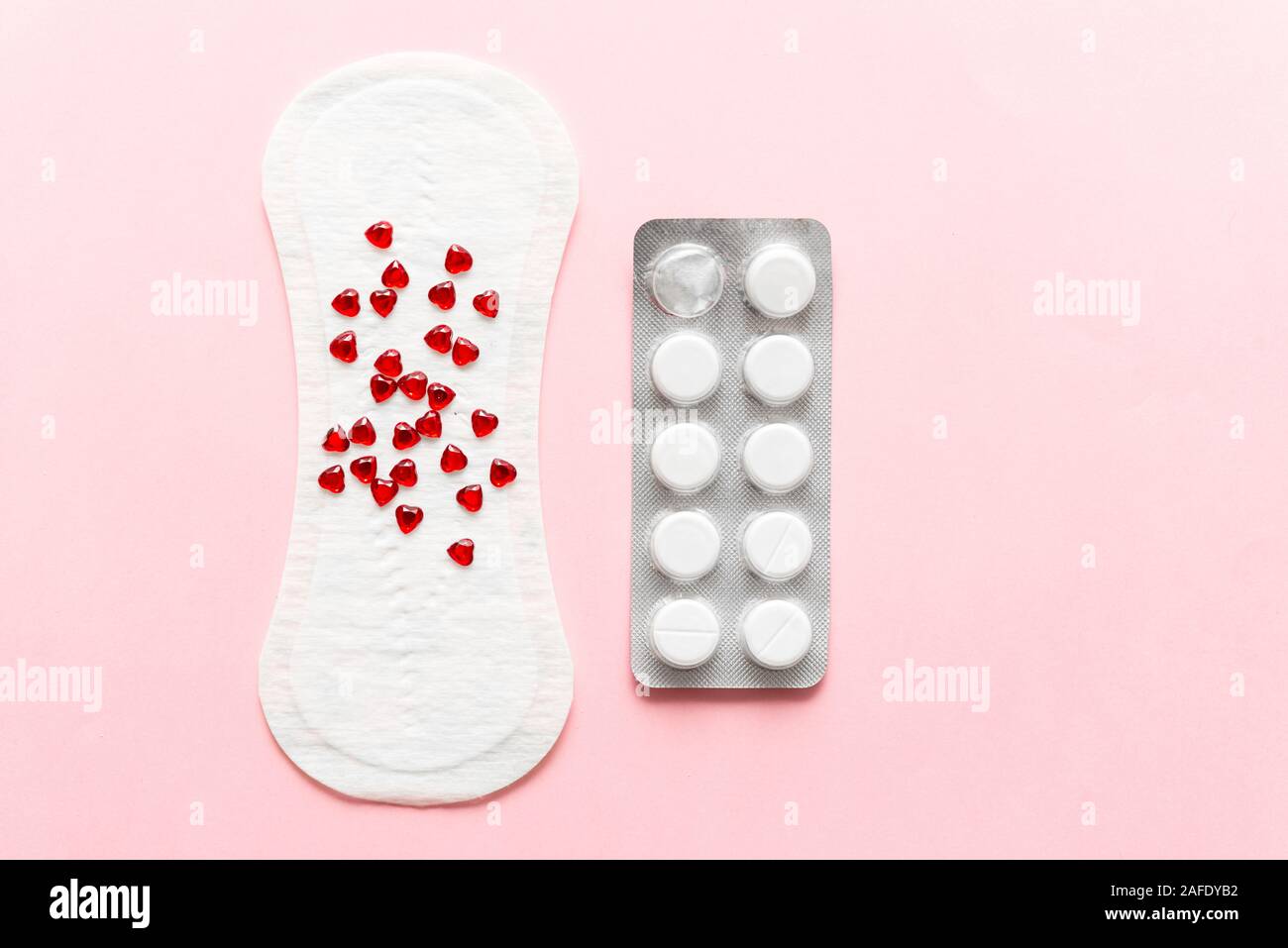 Two pills and menstruation pad with red hearst on it, painkiller ...